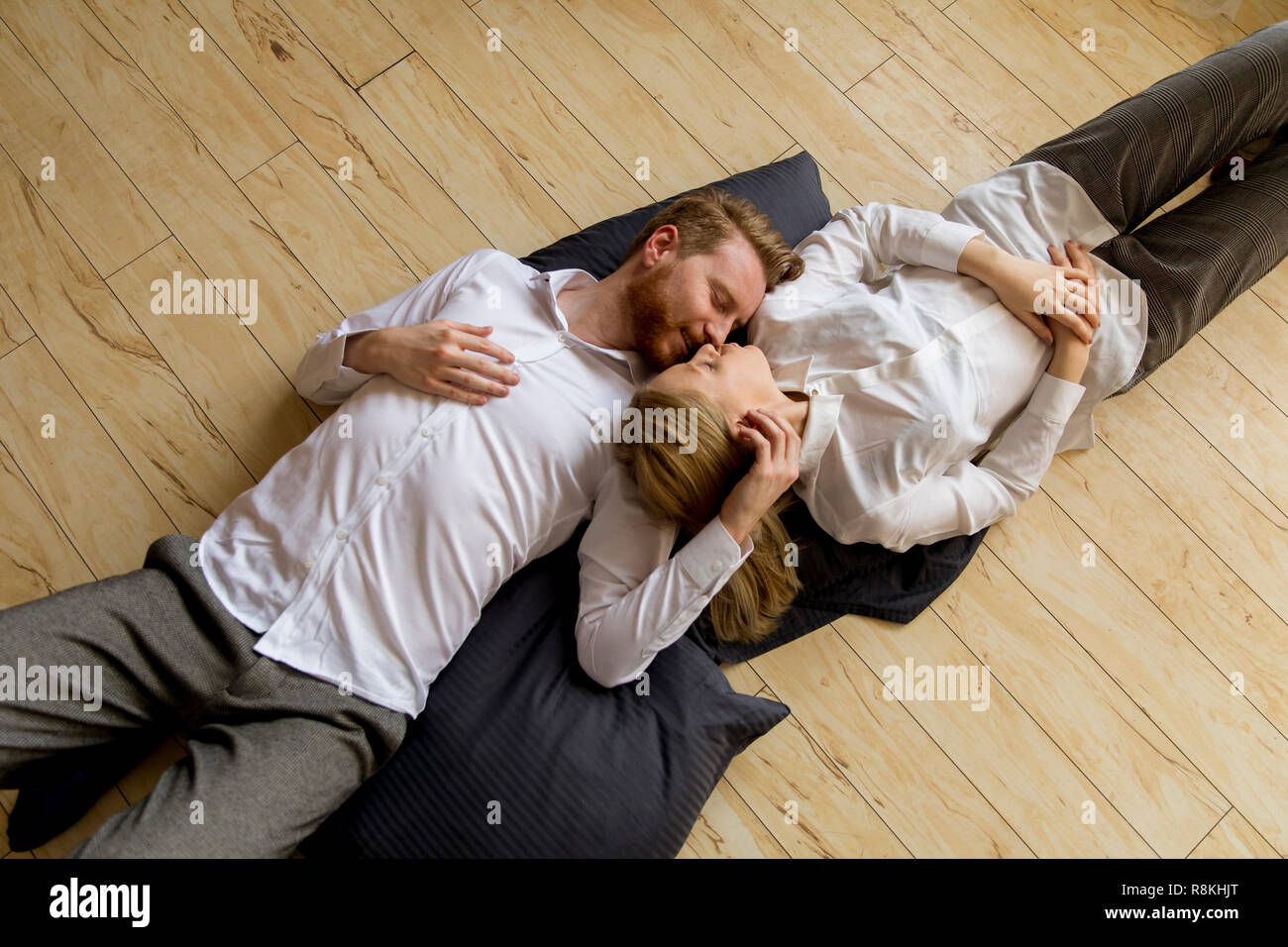 Loving young couple lying and kissing on the floor at home Stock Photo ...