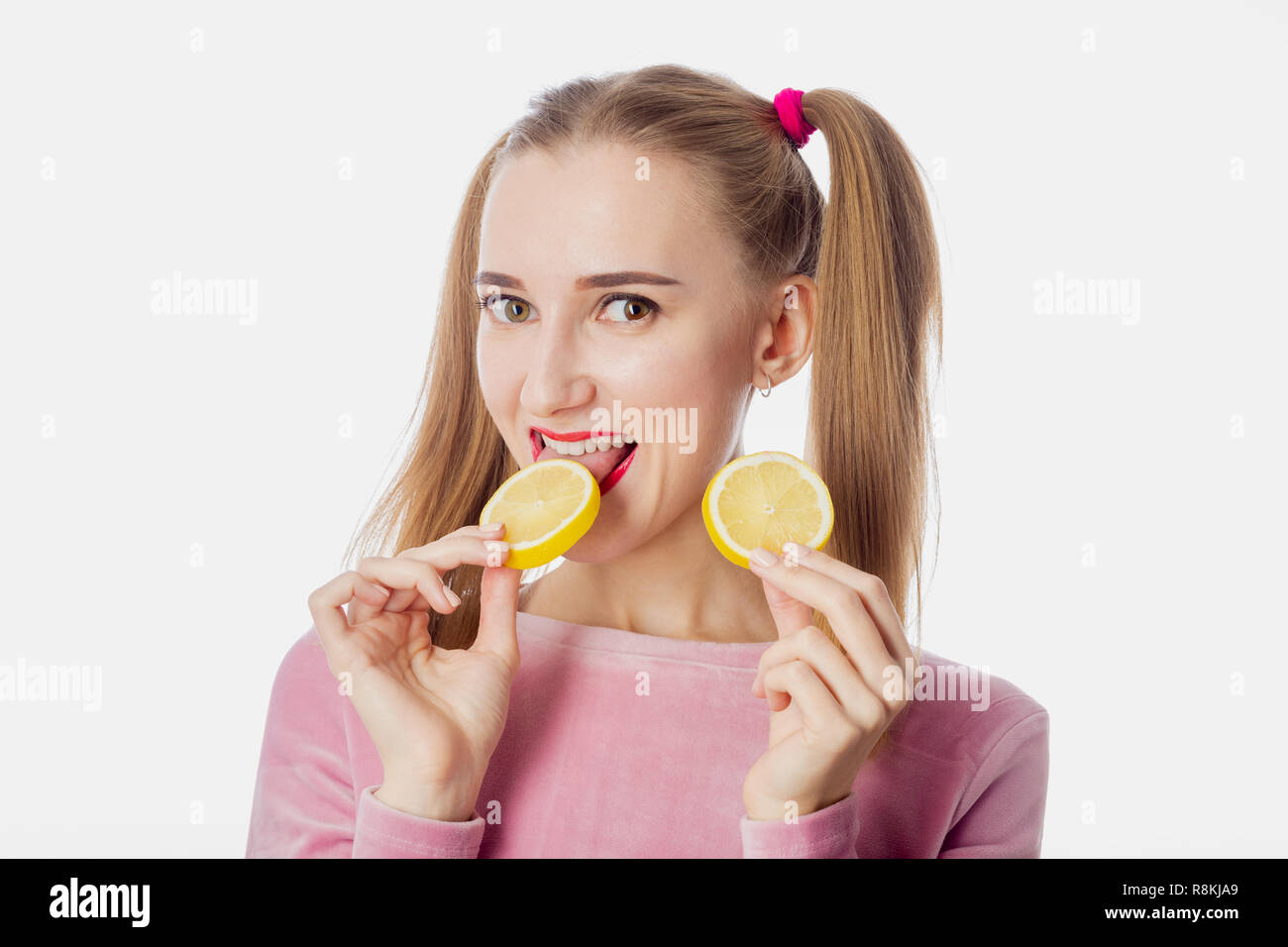 serious fun girl eats lemon on white background looking at camera Stock ...
