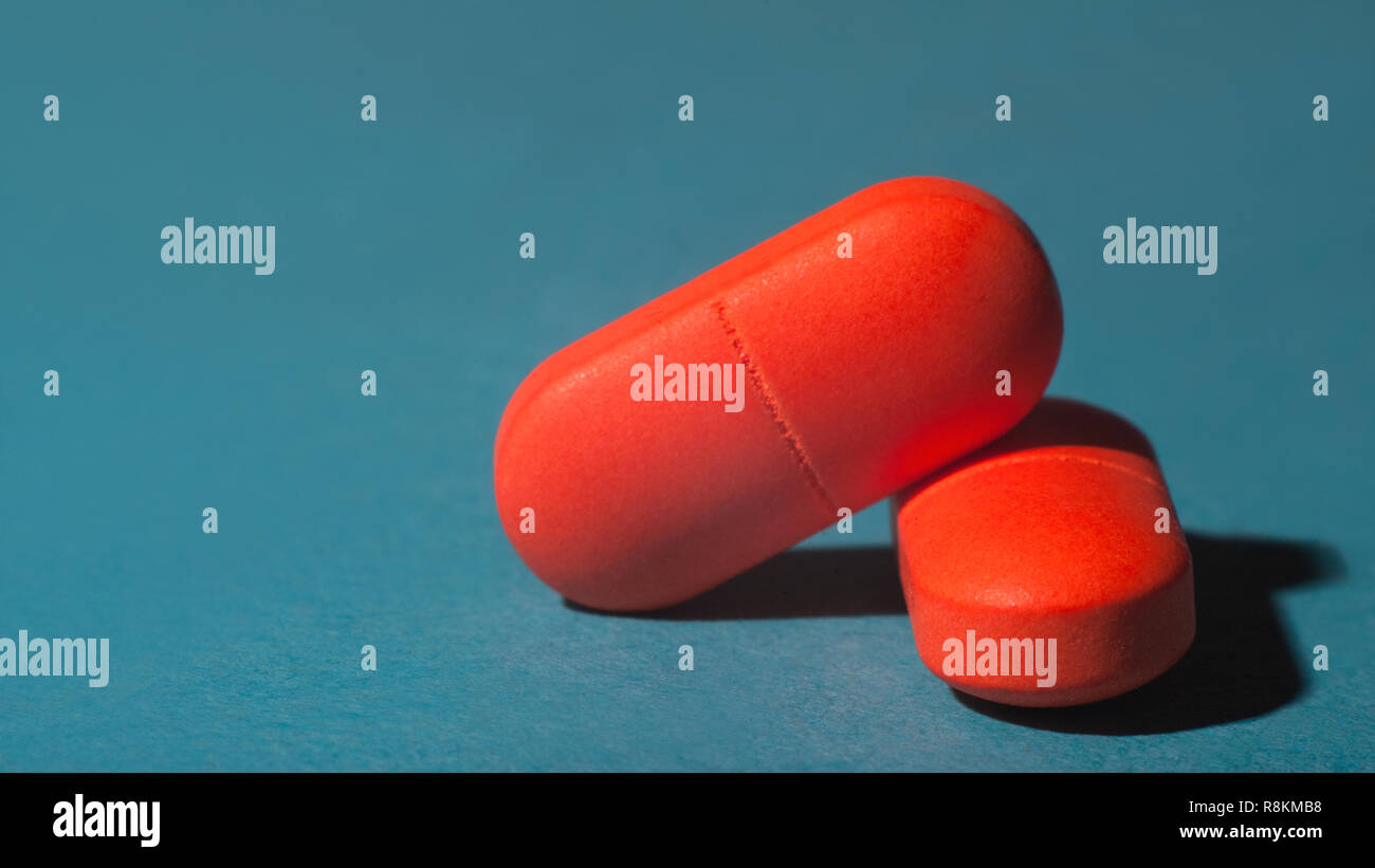 Two red capsules of medical pills isolated background Stock Photo - Alamy