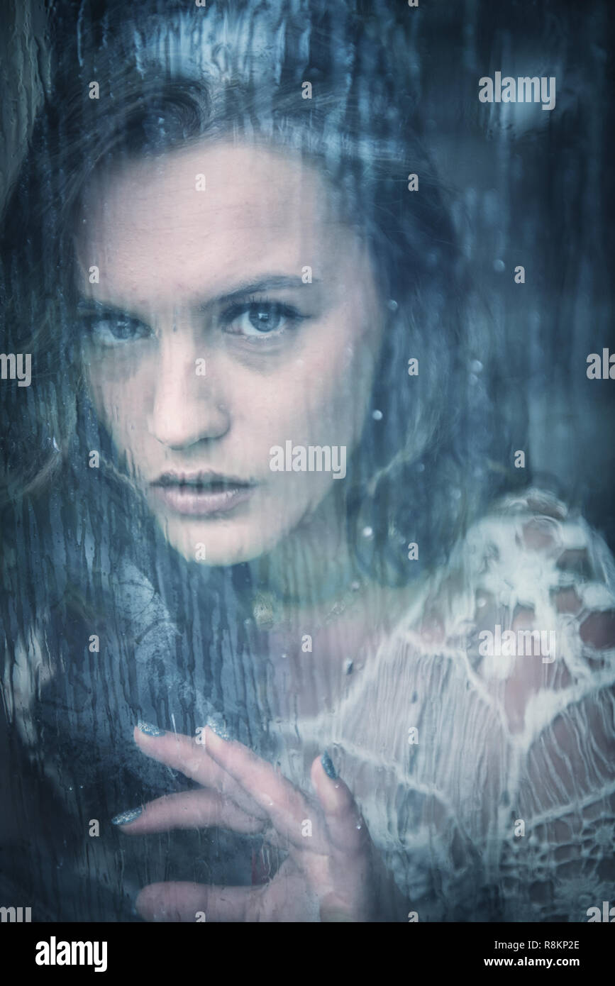 girl looking through rainy window Stock Photo - Alamy