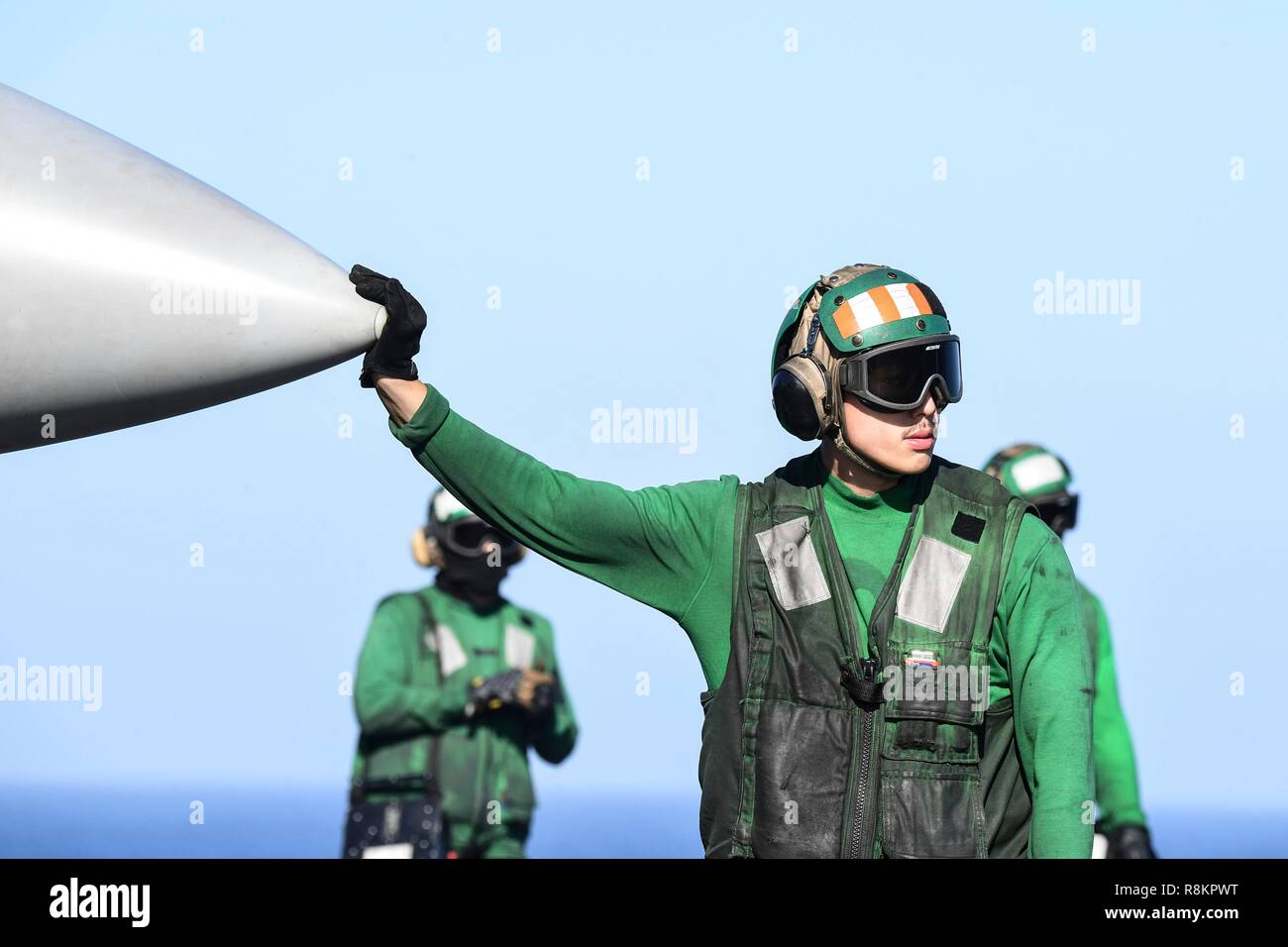 A Hook Runner in a green shirt, observes the launch a F/A-18 Super ...