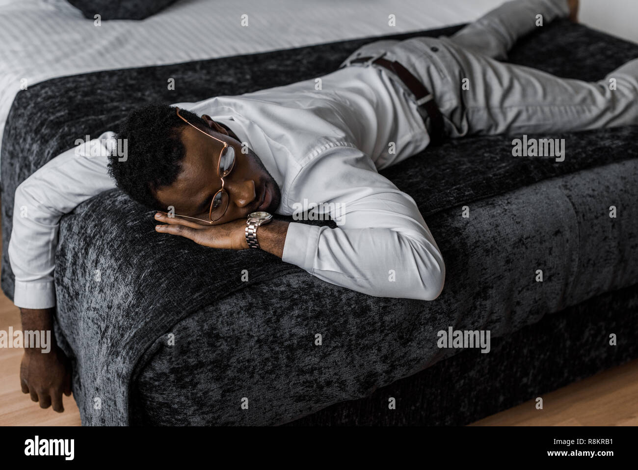 exhausted african american man in formal wear sleeping on bed in hotel ...