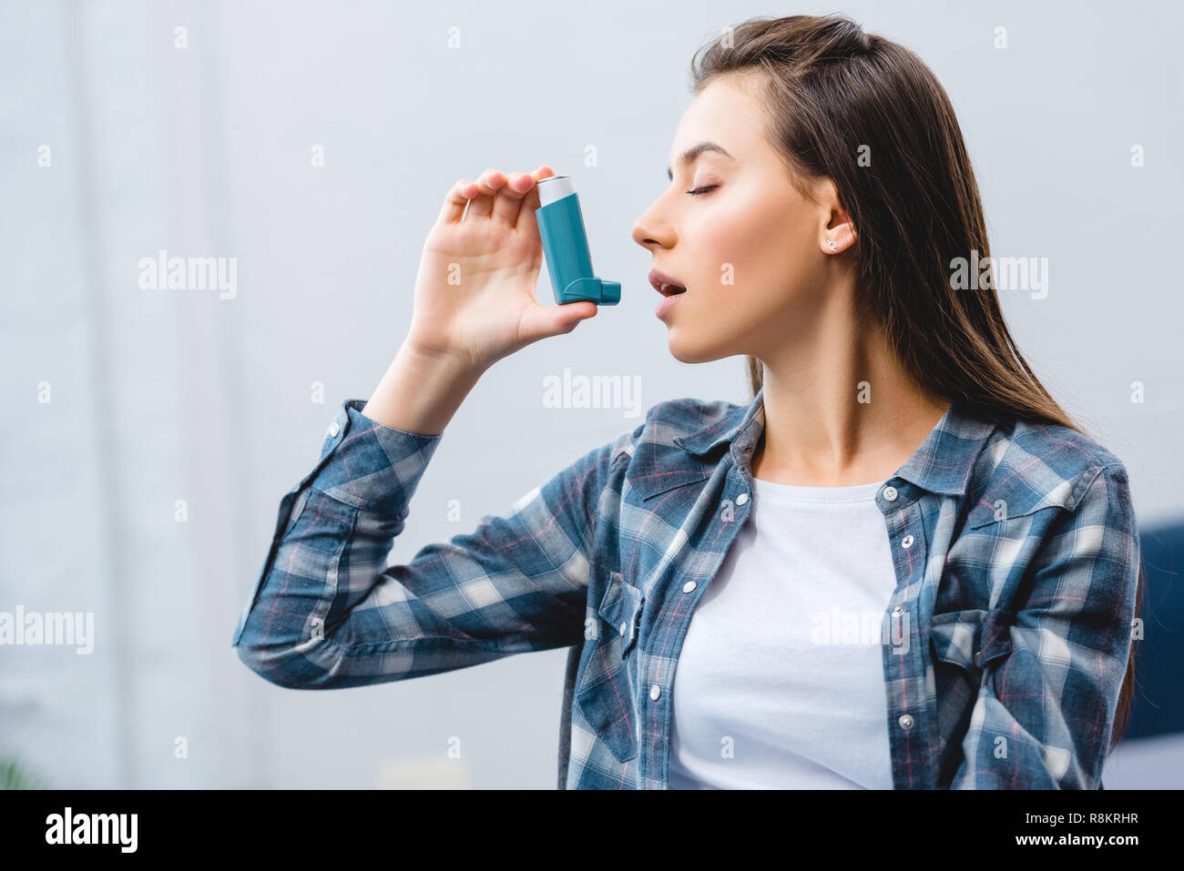 young woman using inhaler while suffering from asthma at home Stock ...