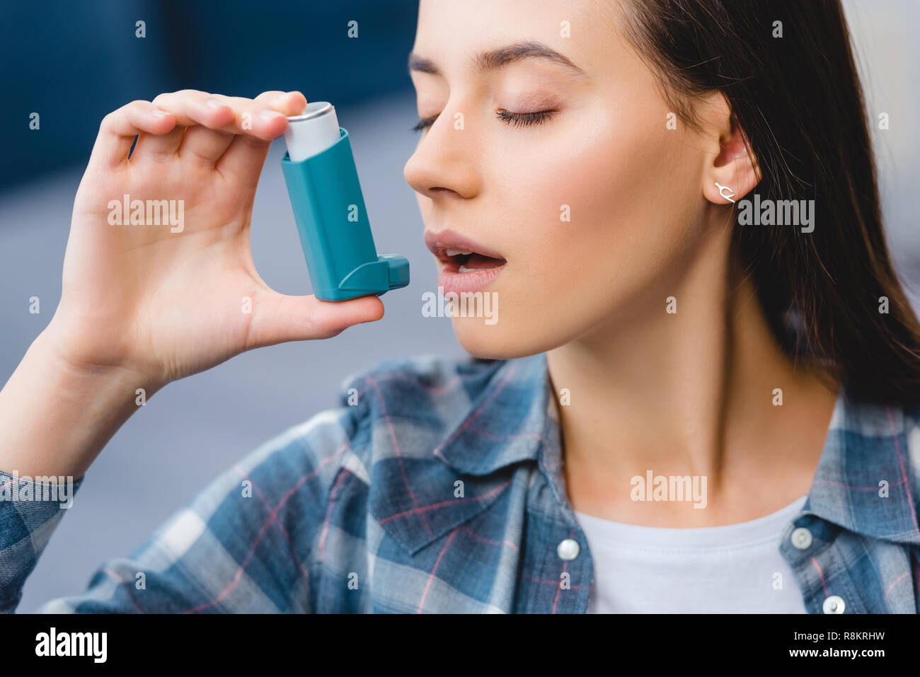 close-up view of young woman using inhaler while suffering from asthma ...