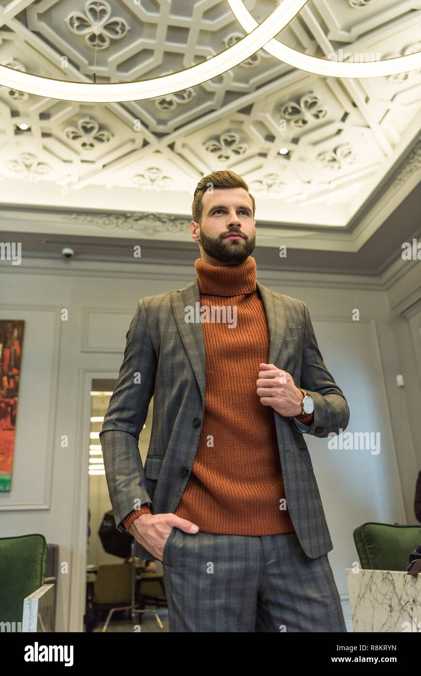 serious handsome man in formal wear posing with hand in pocket in ...