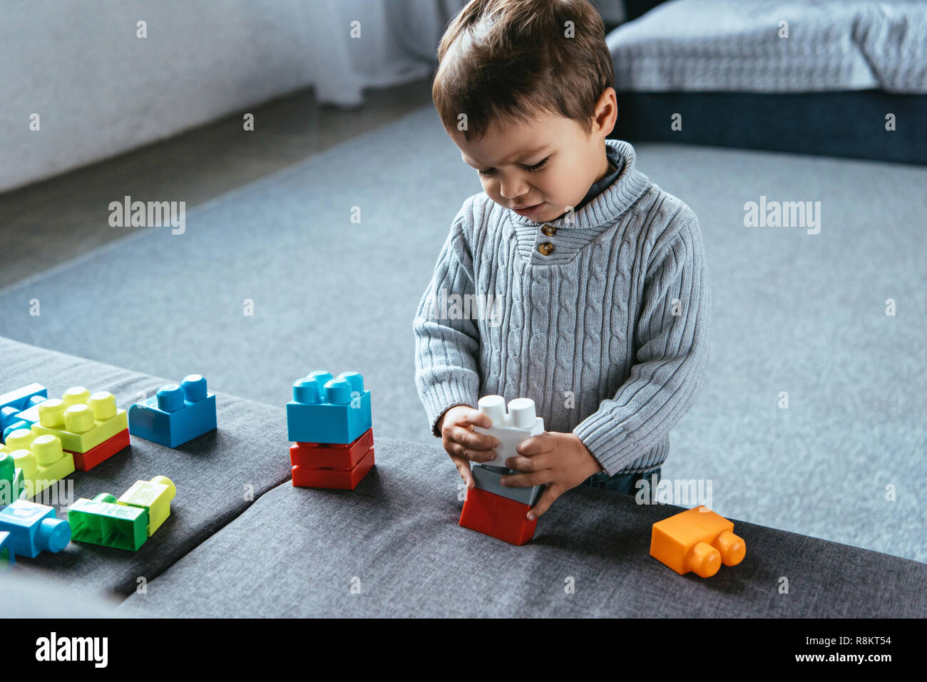 irritated little boy playing with colorful plastic blocks at home Stock ...