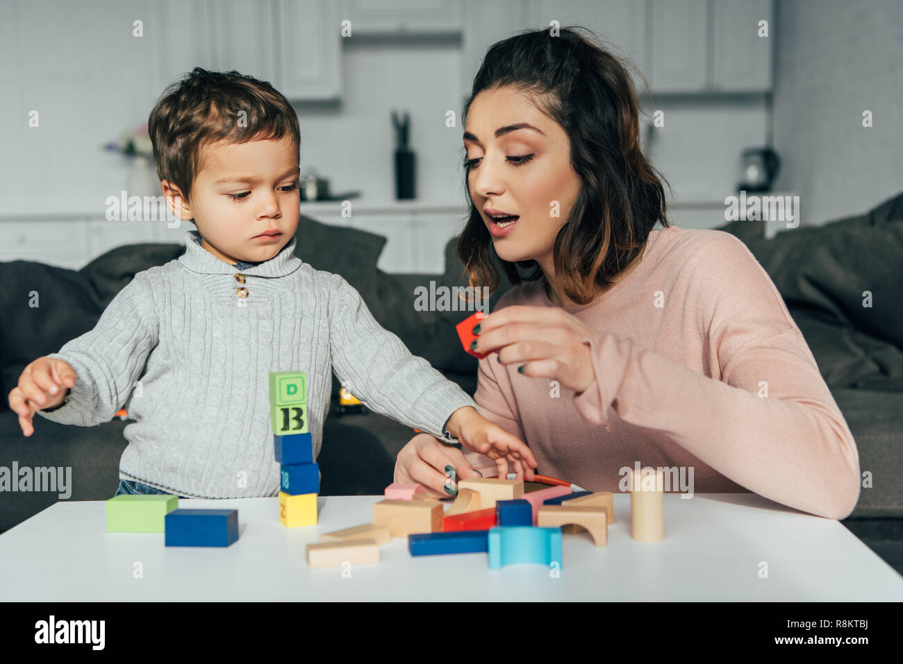 adorable little kid and his mother playing blocks wood tower game at ...