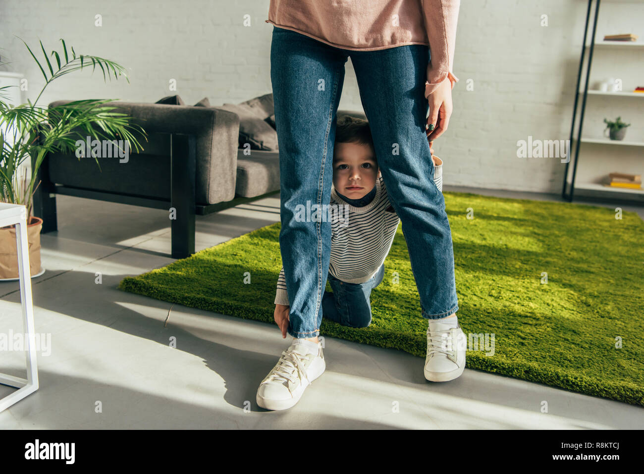 little boy sitting between mother legs in living room at home Stock ...