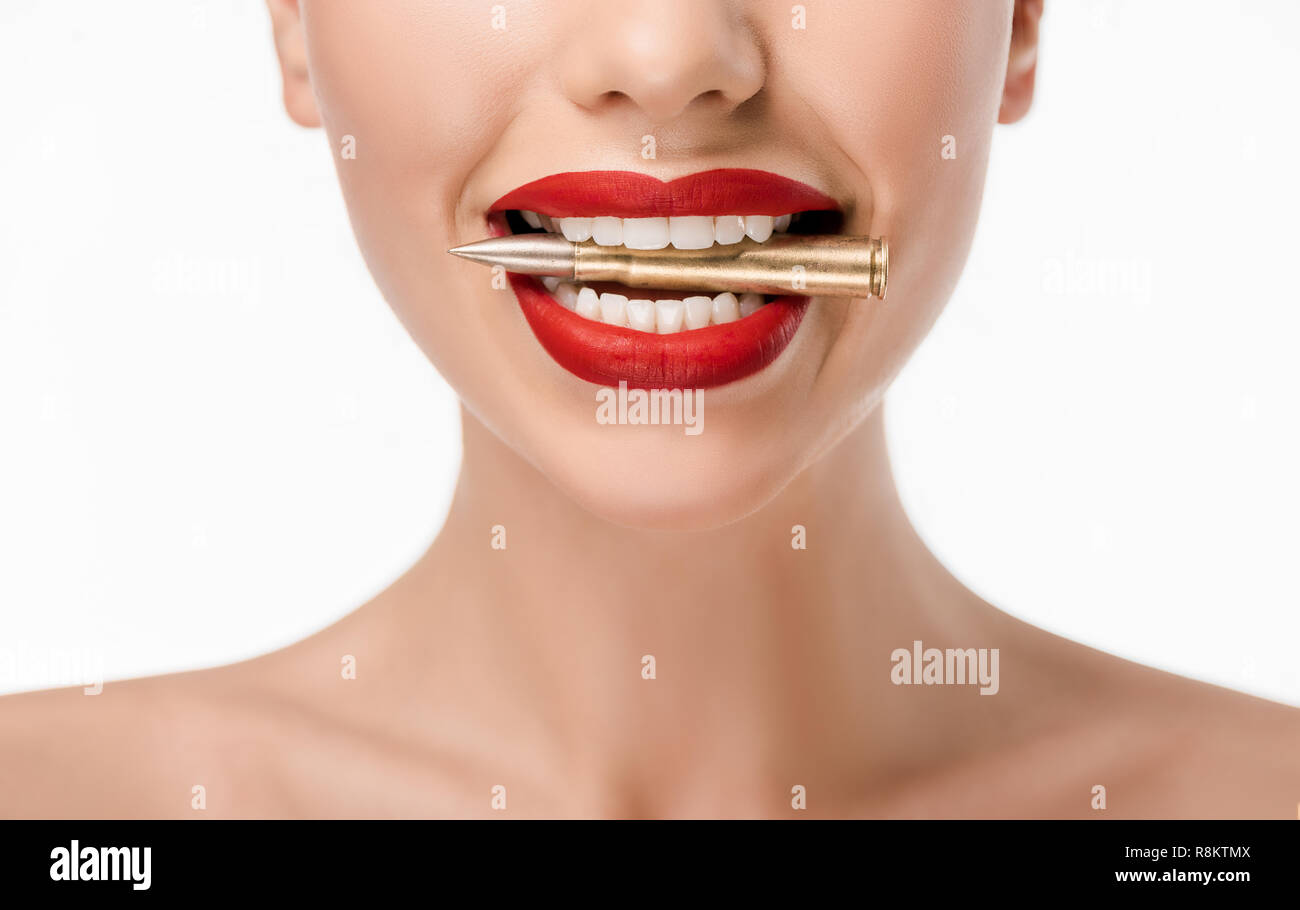 close-up partial view of young woman holding bullet in teeth isolated ...