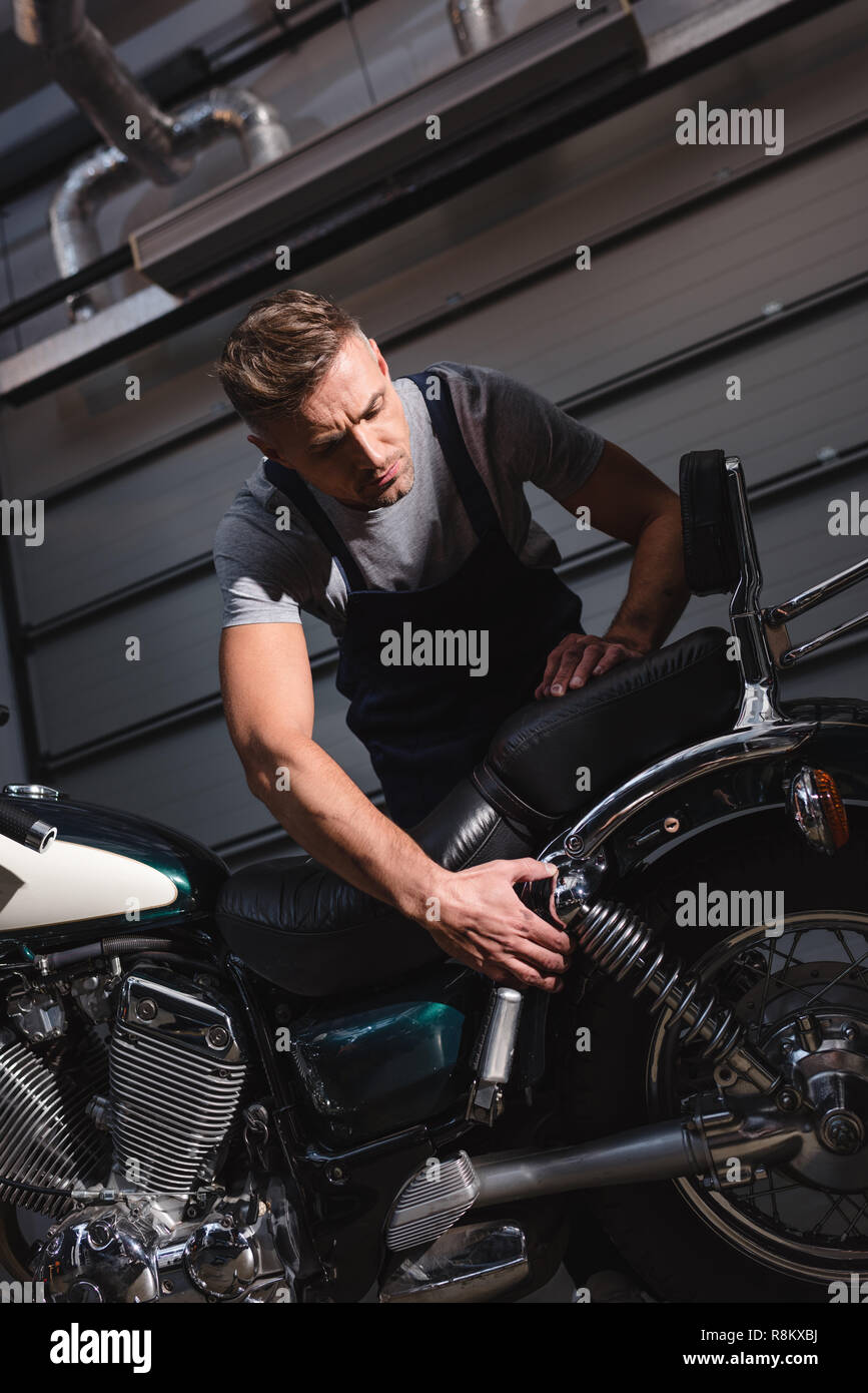 serious mechanic checking back wheel in garage Stock Photo - Alamy