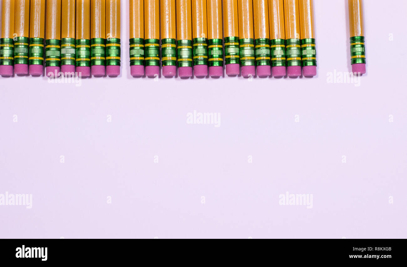 Many pencils in a row showing only the eraser end on white table with ...