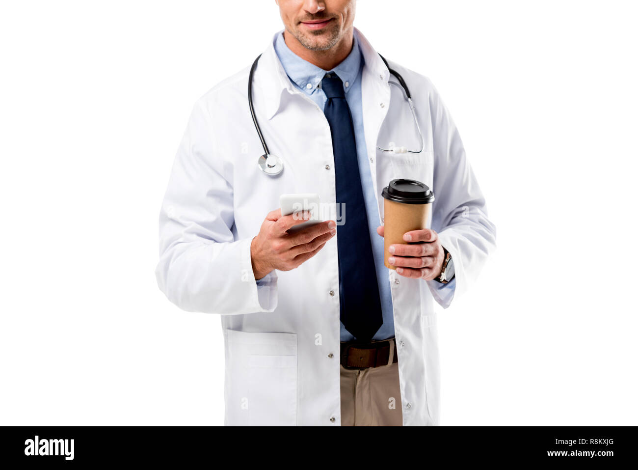 cropped view of doctor holding coffee to go and using smartphone ...