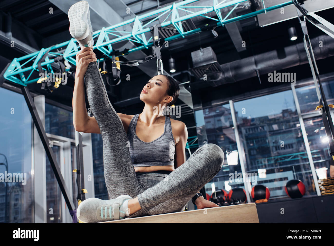 beautiful asian girl with raising leg sitting on cube at gym Stock ...