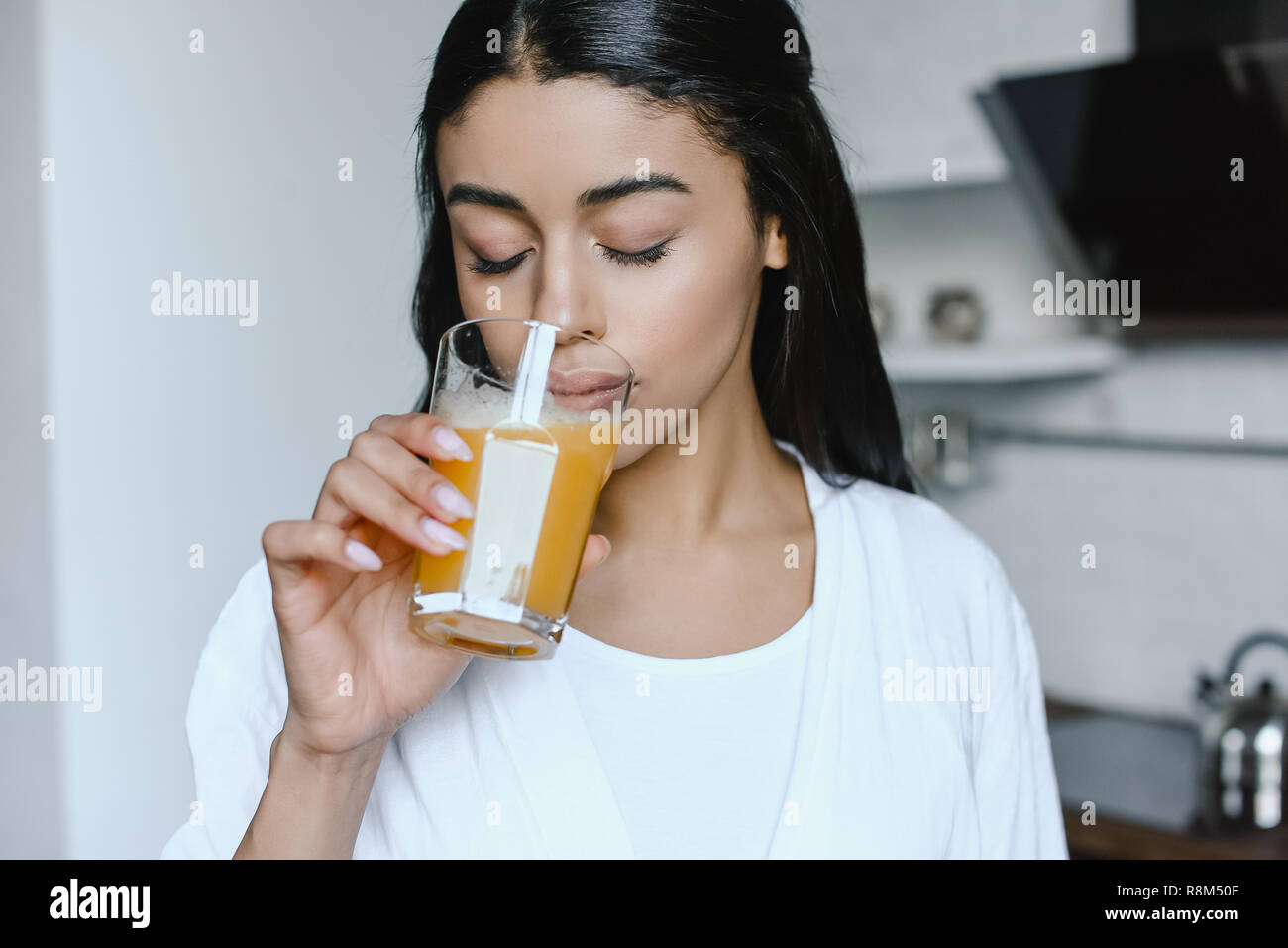 Beautiful Mixed Race Girl In White Robe Drinking Fresh Orange Juice In