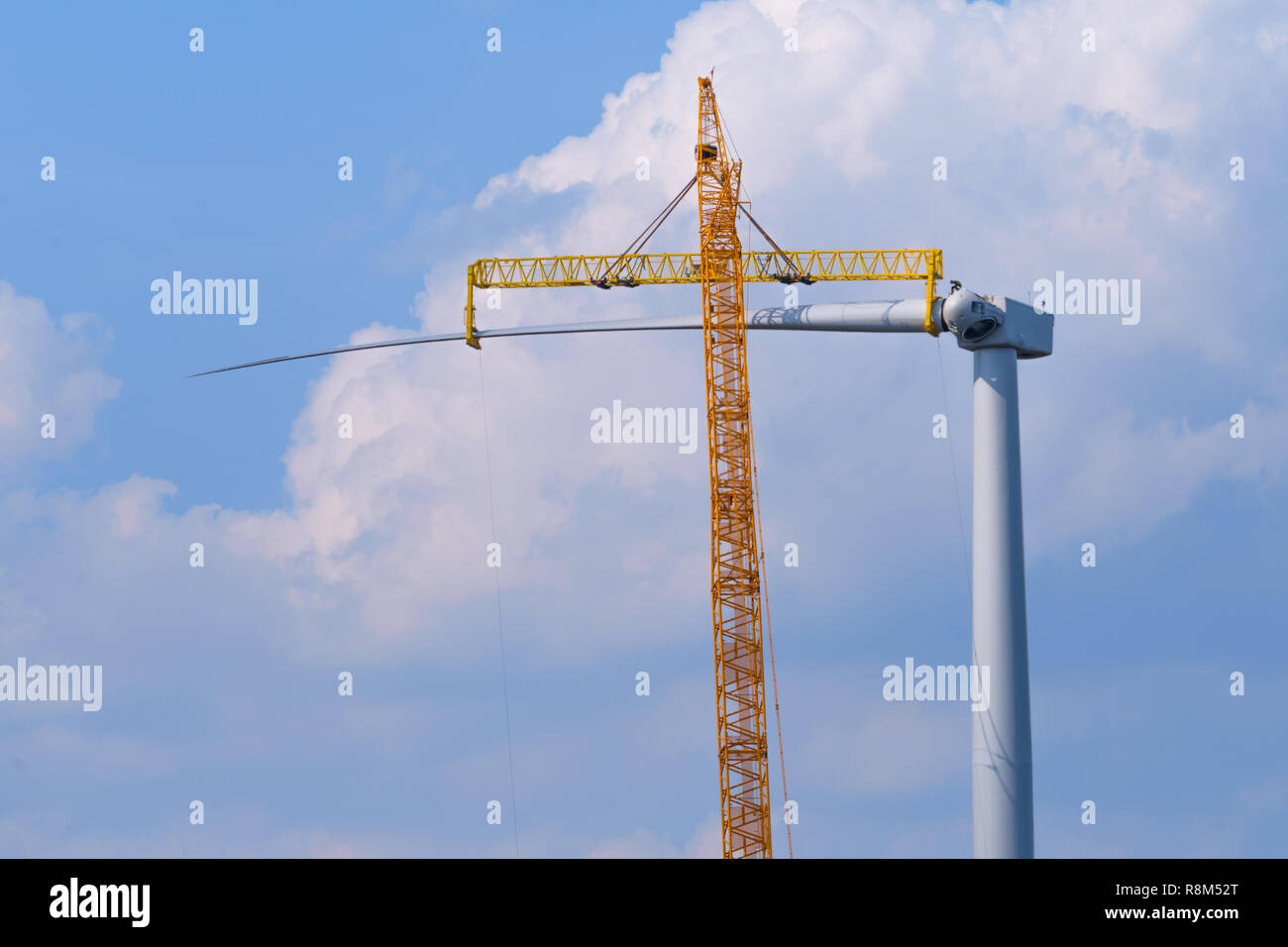 yellow crane tower placing windmill blade with background of blue sky ...