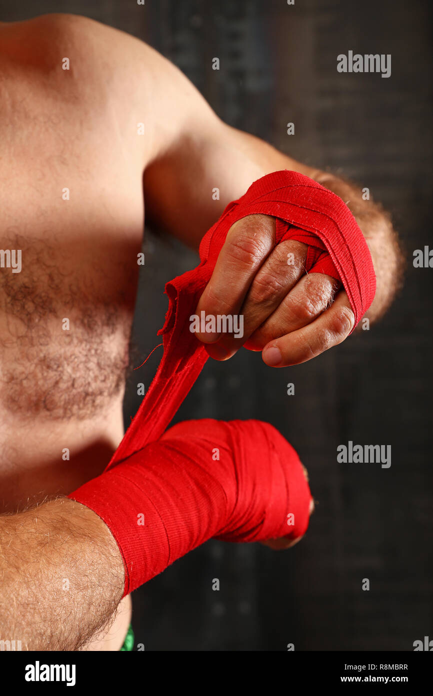 Close up man boxer wrapping red hand wraps over wrists preparing for ...