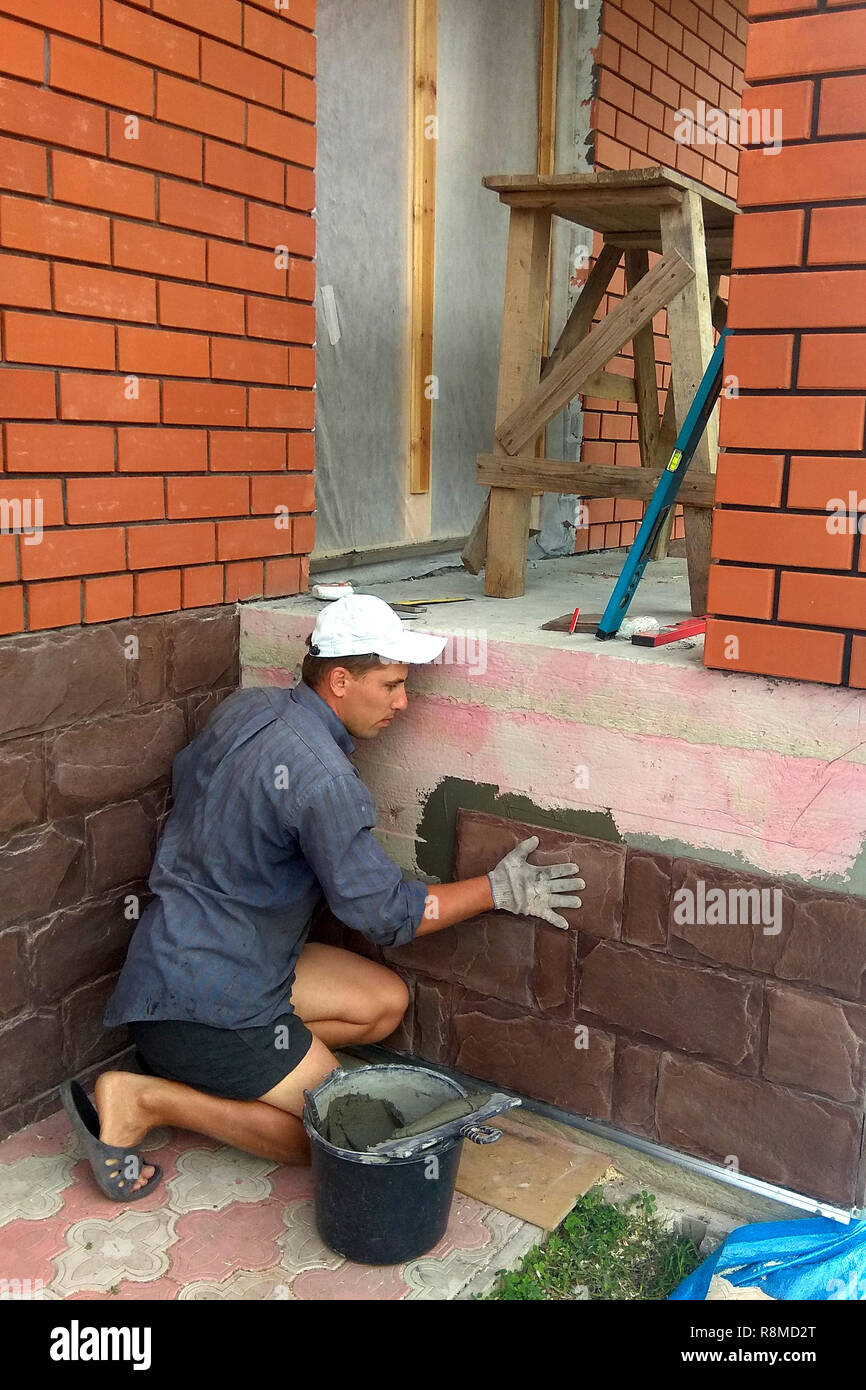 gluing a granite stone on the foundation of the building facing 2018 ...
