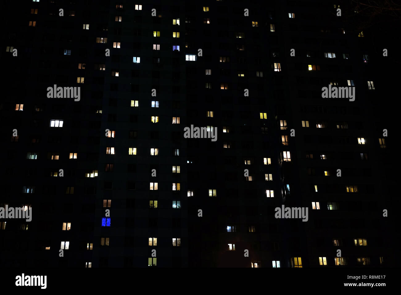 Facade of large multi-storey block of flats with many bright lighting ...