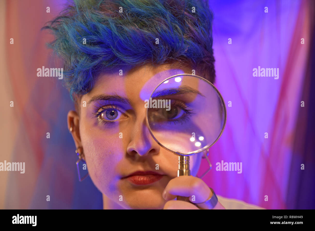 Young girl poses with a magnifying glass on the eye Stock Photo - Alamy