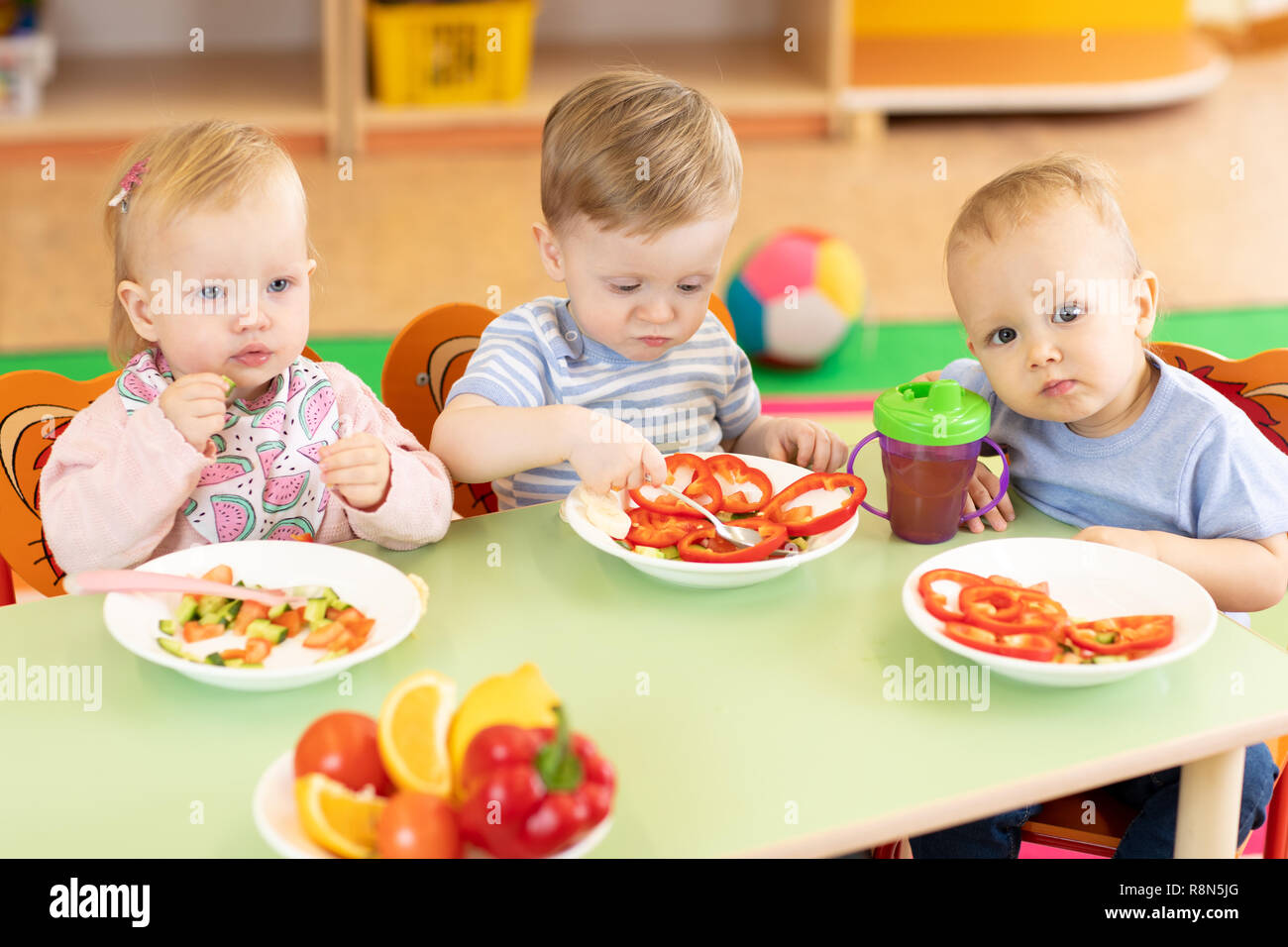Lunch in kindergarden. Babies eating healthy food Stock Photo - Alamy