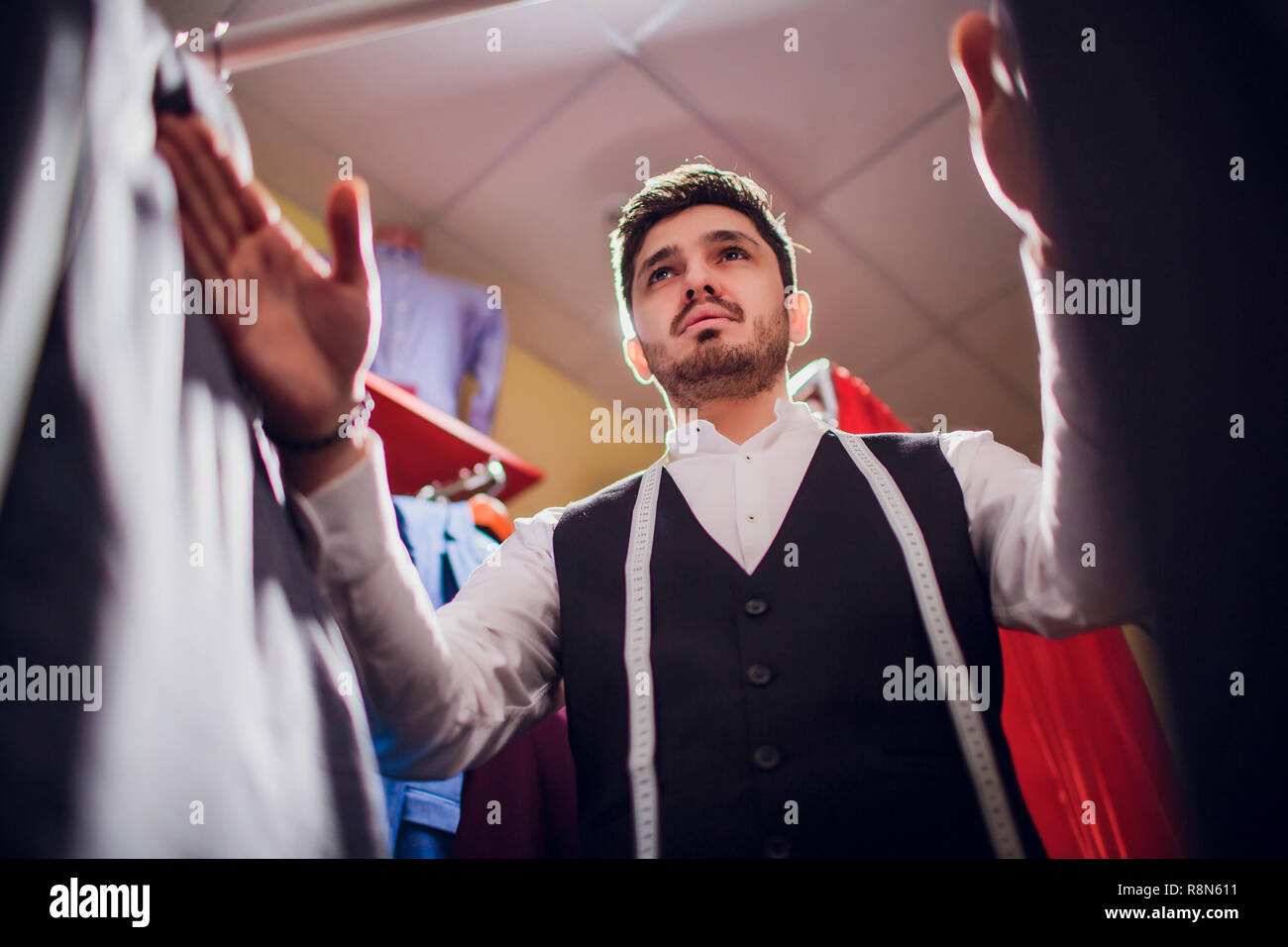 Over shoulder view bearded fashion designer fitting bespoke suit to ...