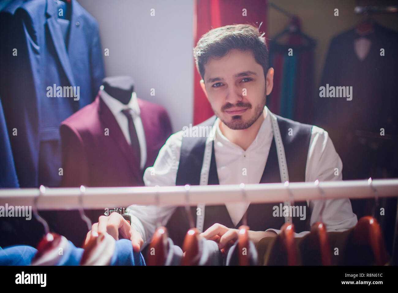 Over shoulder view bearded fashion designer fitting bespoke suit to ...