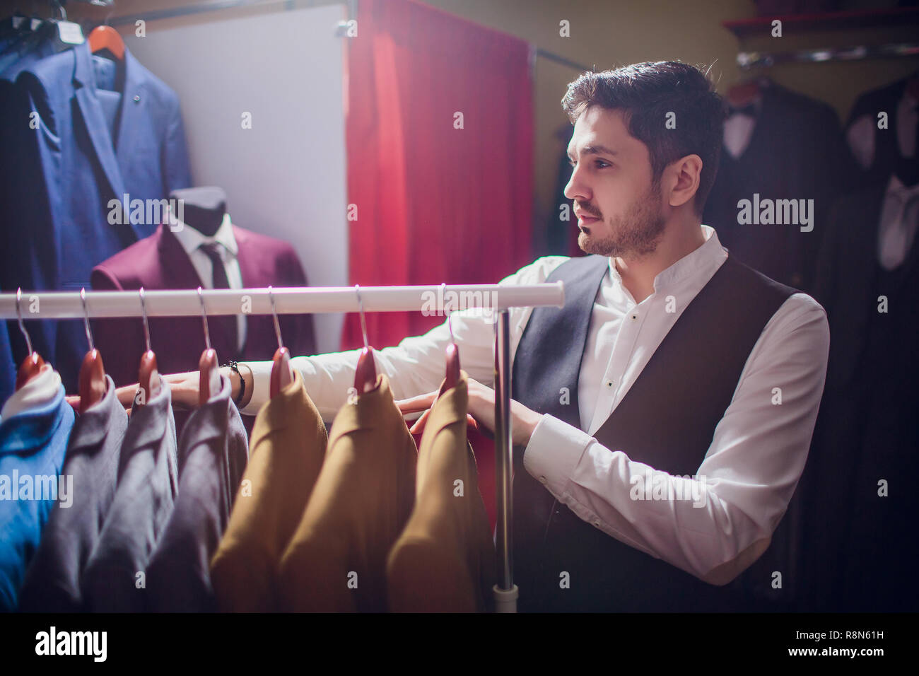 Over shoulder view bearded fashion designer fitting bespoke suit to ...