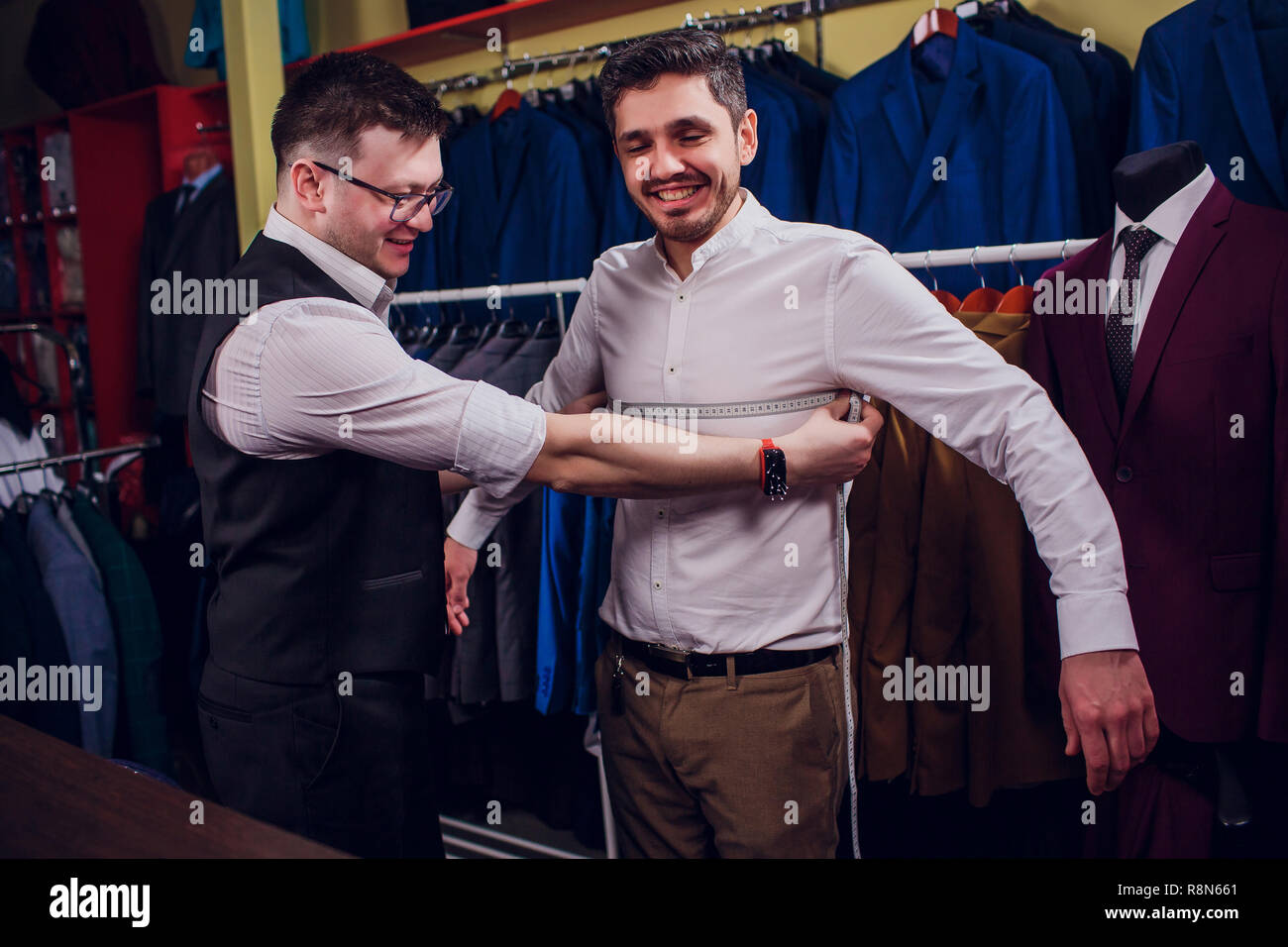 Businessman in classic vest against row suits in shop. Man helps ...