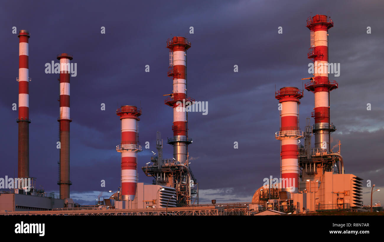 Part of the many chimneys of a big oil refinery in an overcast night ...