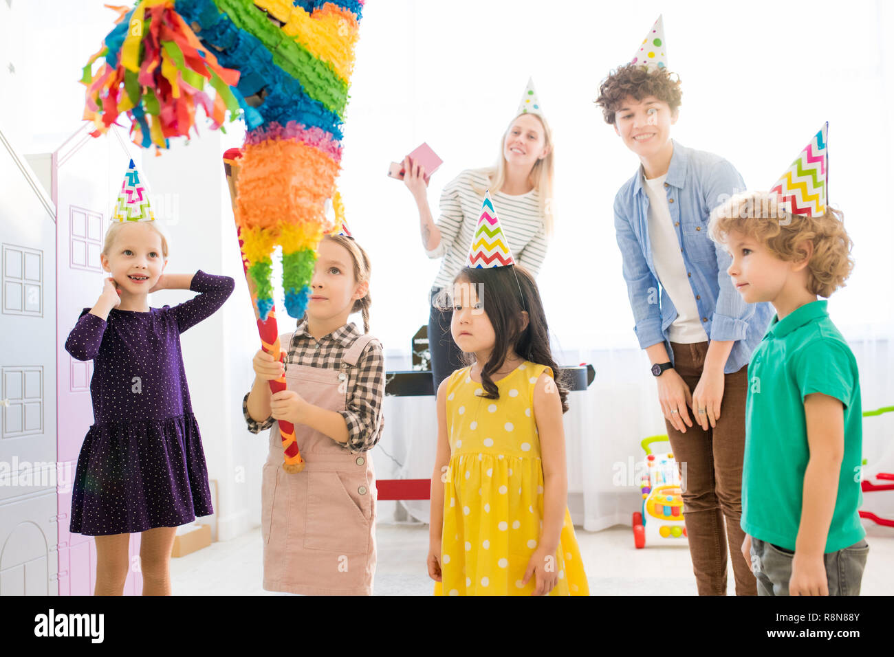 Girl striking pinata at birthday party Stock Photo - Alamy