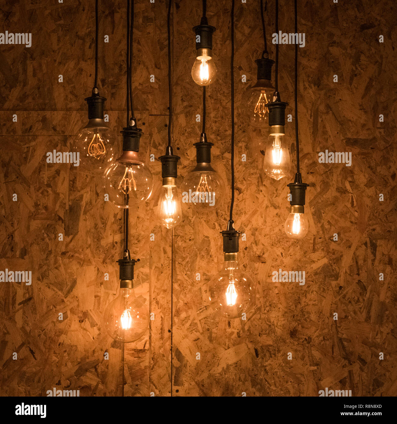 Multiple light bulbs hanging from ceiling against a wooden background ... Multiple light bulbs hanging from ceiling against a wooden background ...