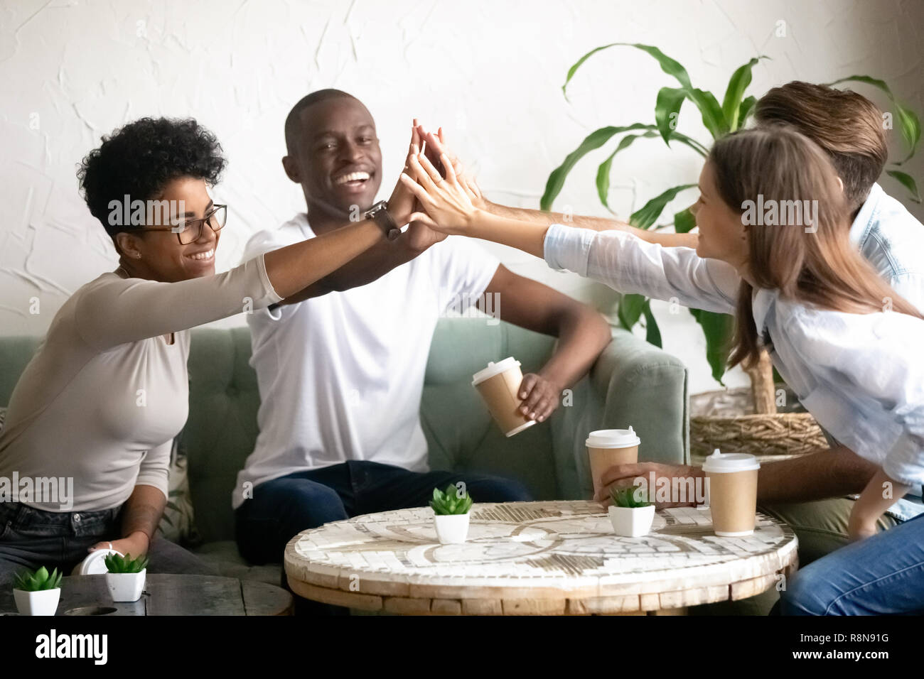 Happy diverse friends giving high five together in cafe Stock Photo - Alamy