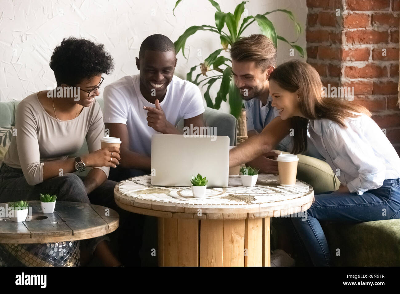 Happy smiling diverse friends using laptop together in cafe Stock Photo ...