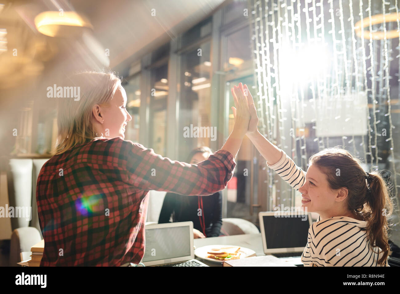 Girls giving high five in cafe Stock Photo - Alamy