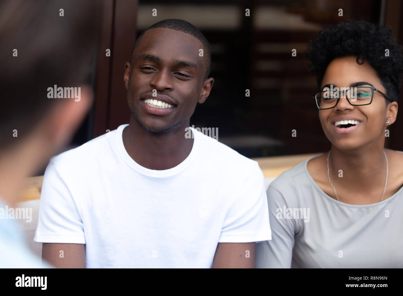 Happy African American couple talking with friend in cafe Stock Photo ...