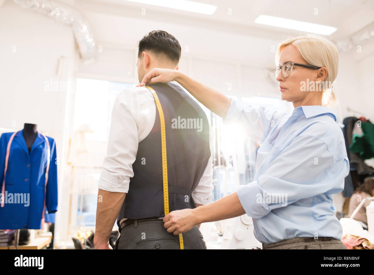 Female Tailor Measuring Client in Atelier Stock Photo - Alamy
