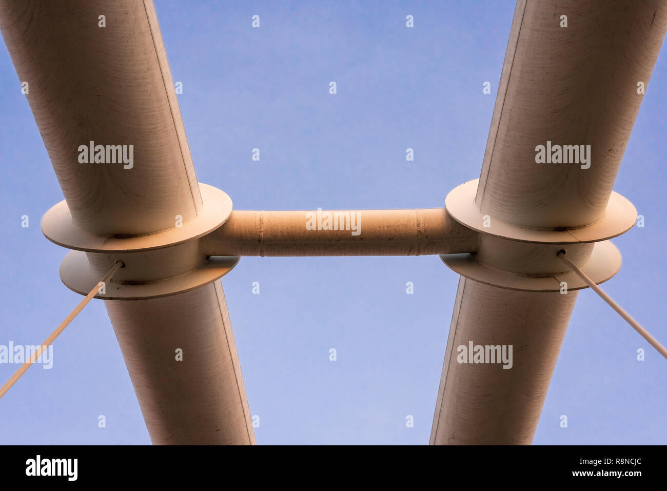 Symmetrical steel pipes supporting a suspension bridge over a river ...