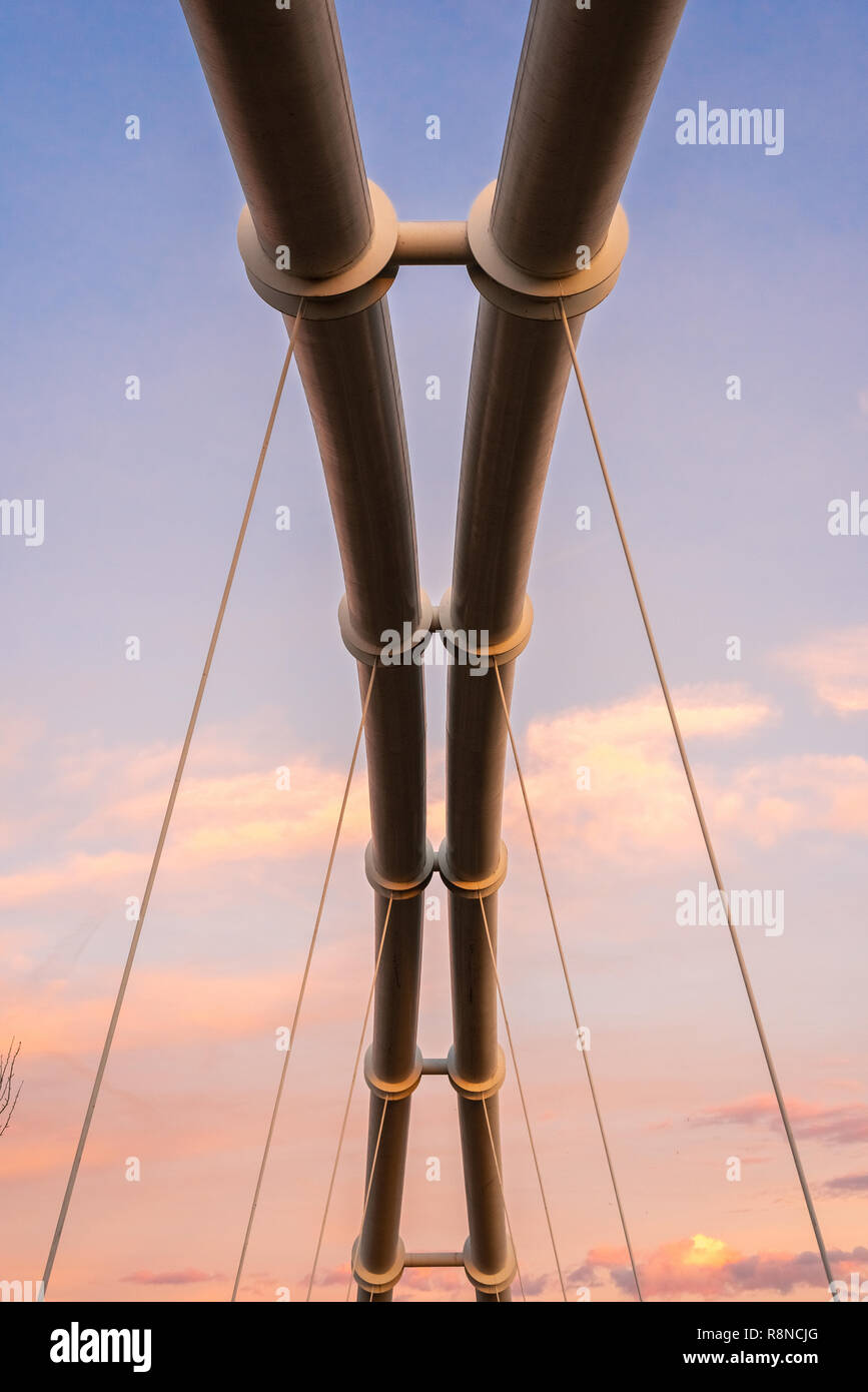 Symmetrical steel pipes supporting a suspension bridge over a river ...