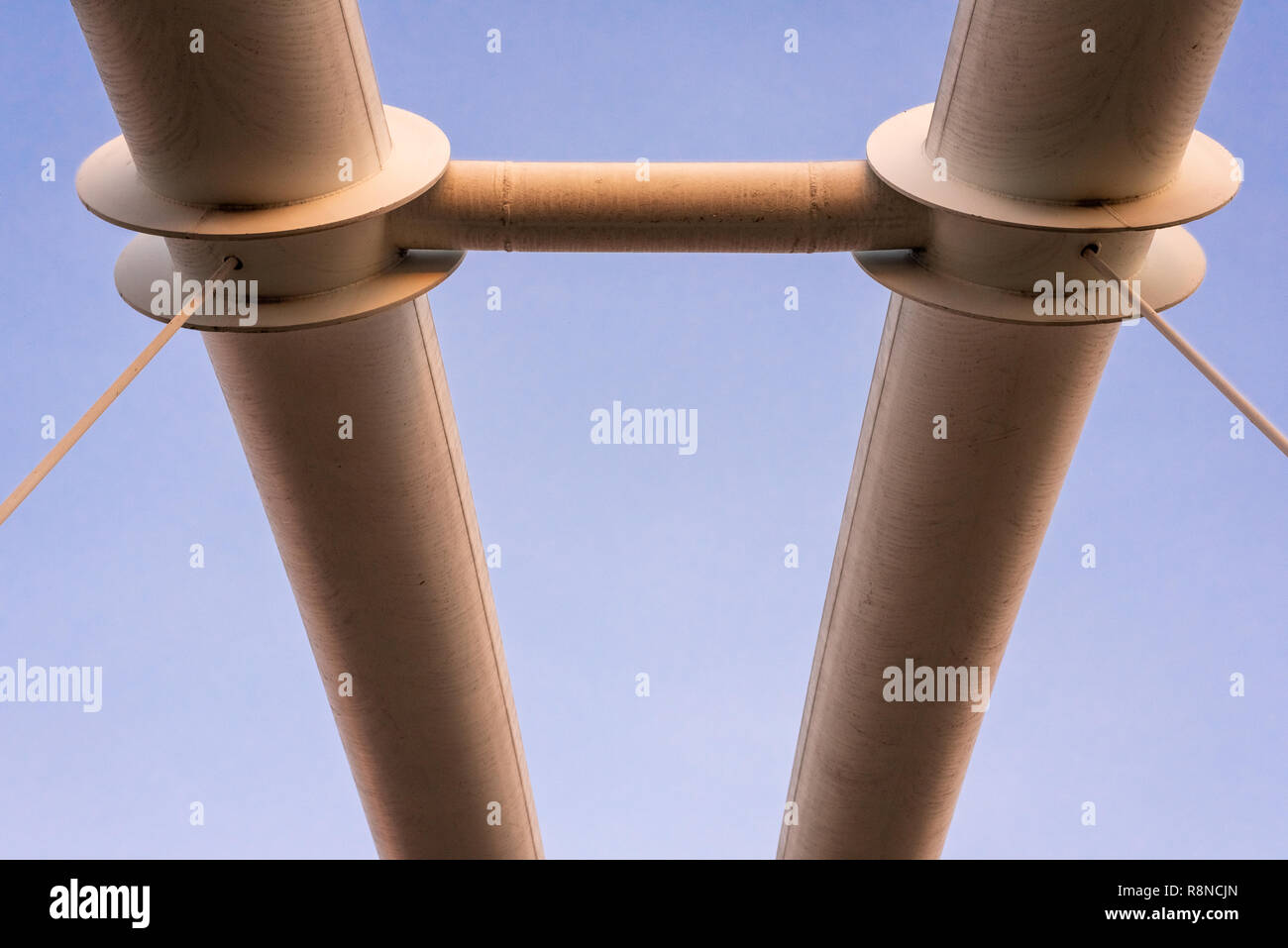 Symmetrical steel pipes supporting a suspension bridge over a river ...