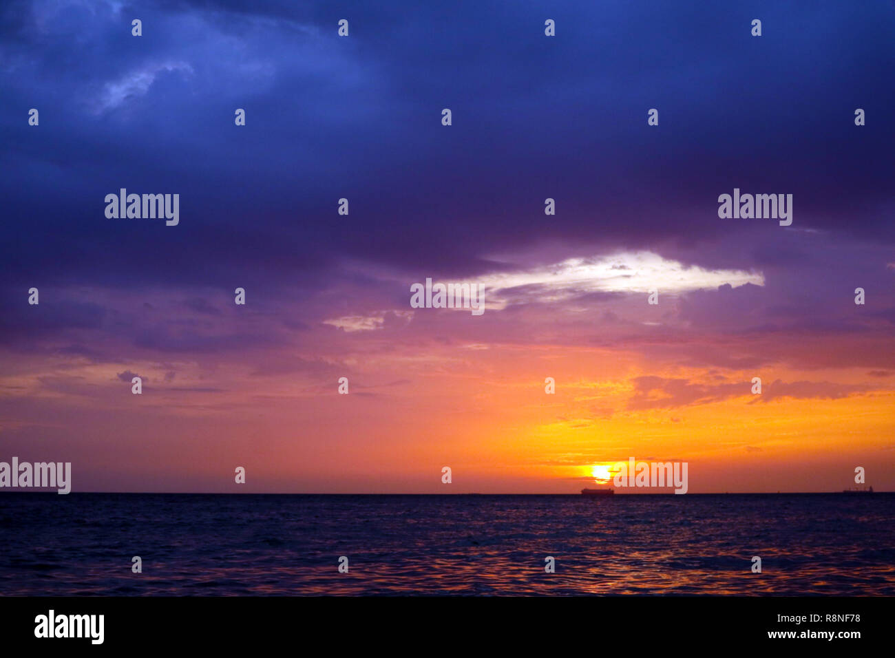 sunset and ship on horizontal ocean water surface and colorful cloud ...