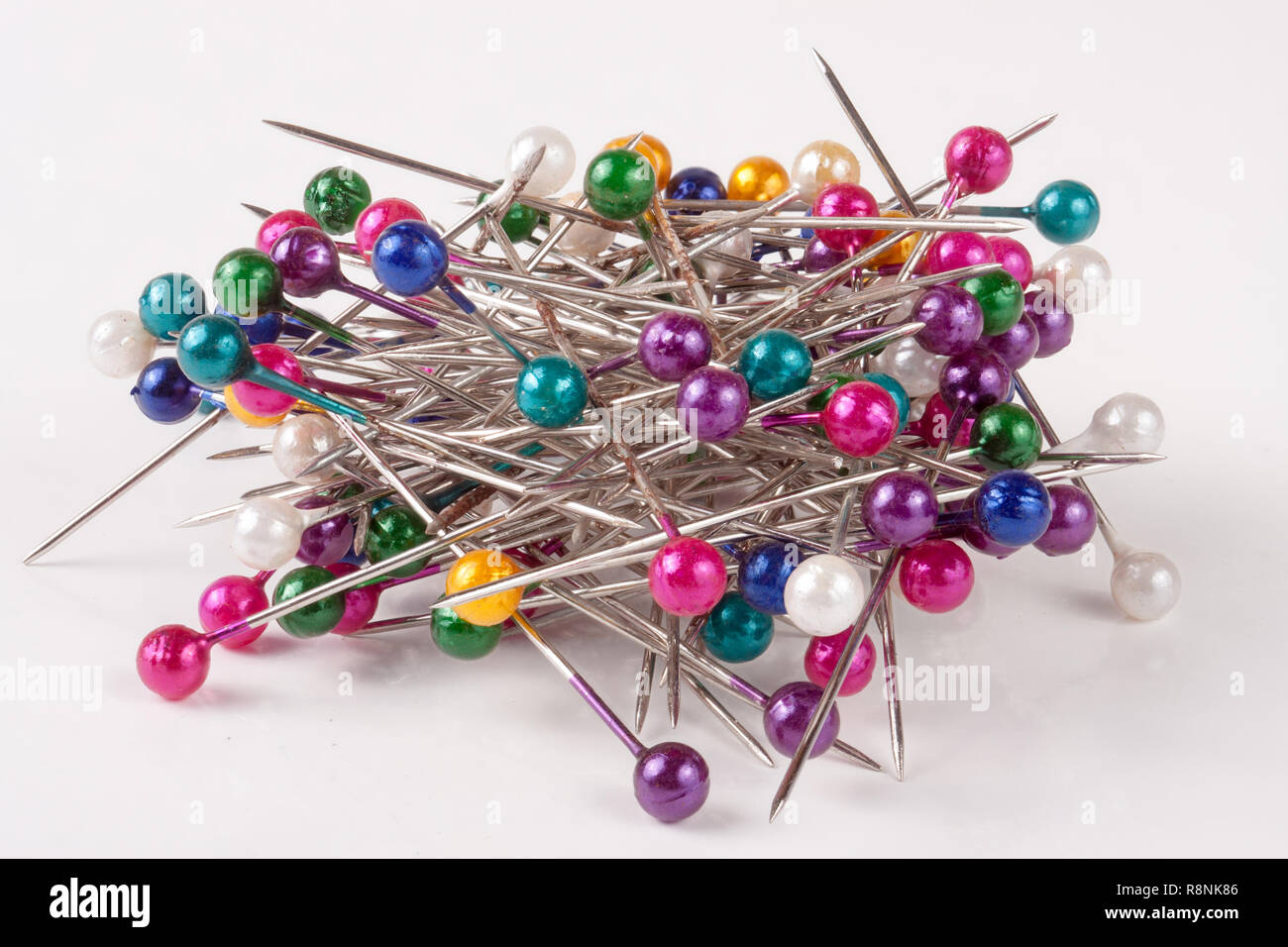 pile of multi-colored sewing pins on a white background Stock Photo - Alamy