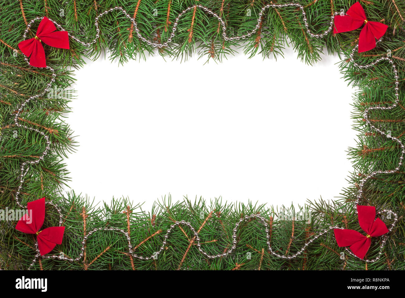 Christmas frame made of fir branches decorated with beads and red bows ...