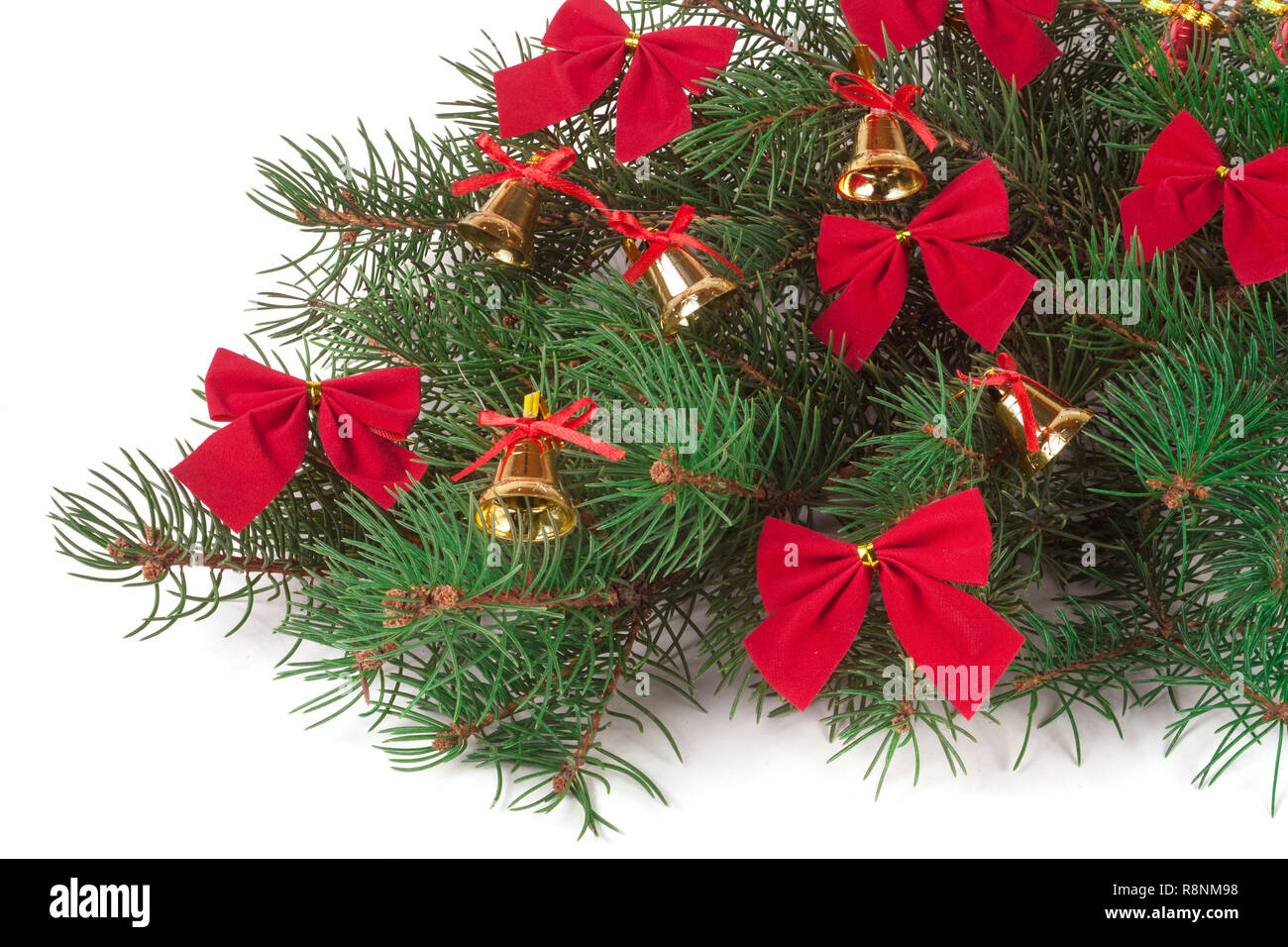 branch of Christmas tree decorated bells and bows isolated on white ...