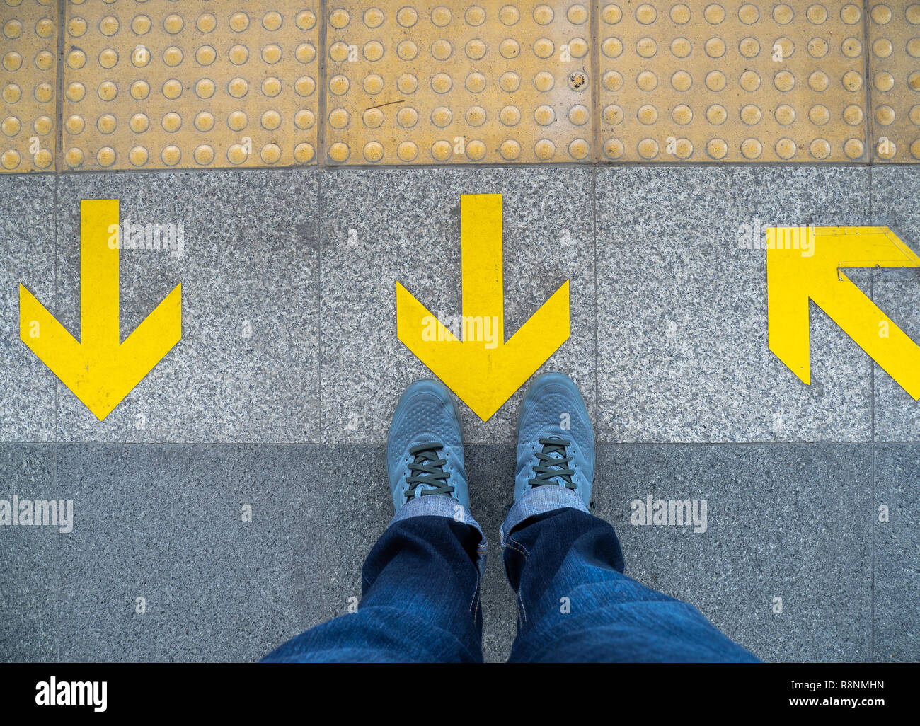 Top view of man feet standing over Arrow symbol on subway platform ...