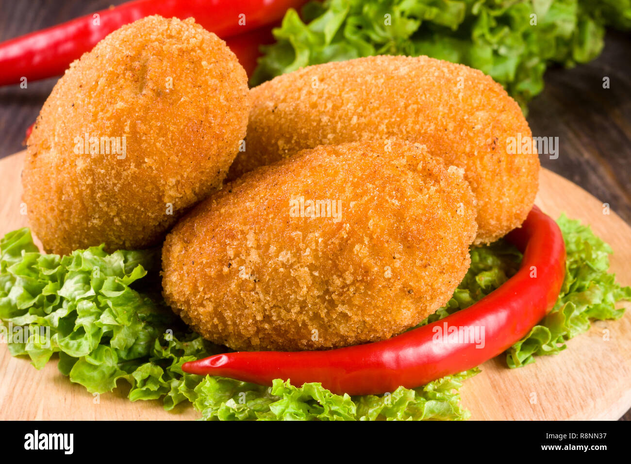 three fried breaded cutlet with lettuce on a cutting board Stock Photo ...