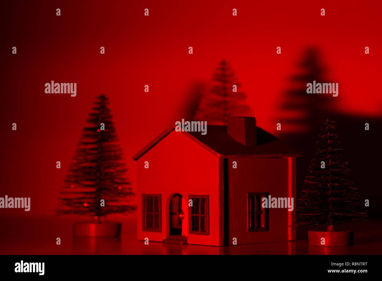 Colored with red light Handmade small house with 3 pine trees on a red ...