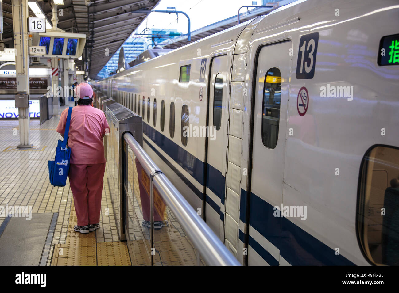 A shinkansen cleaning lady waiting to board the incoming train at Tokyo ...