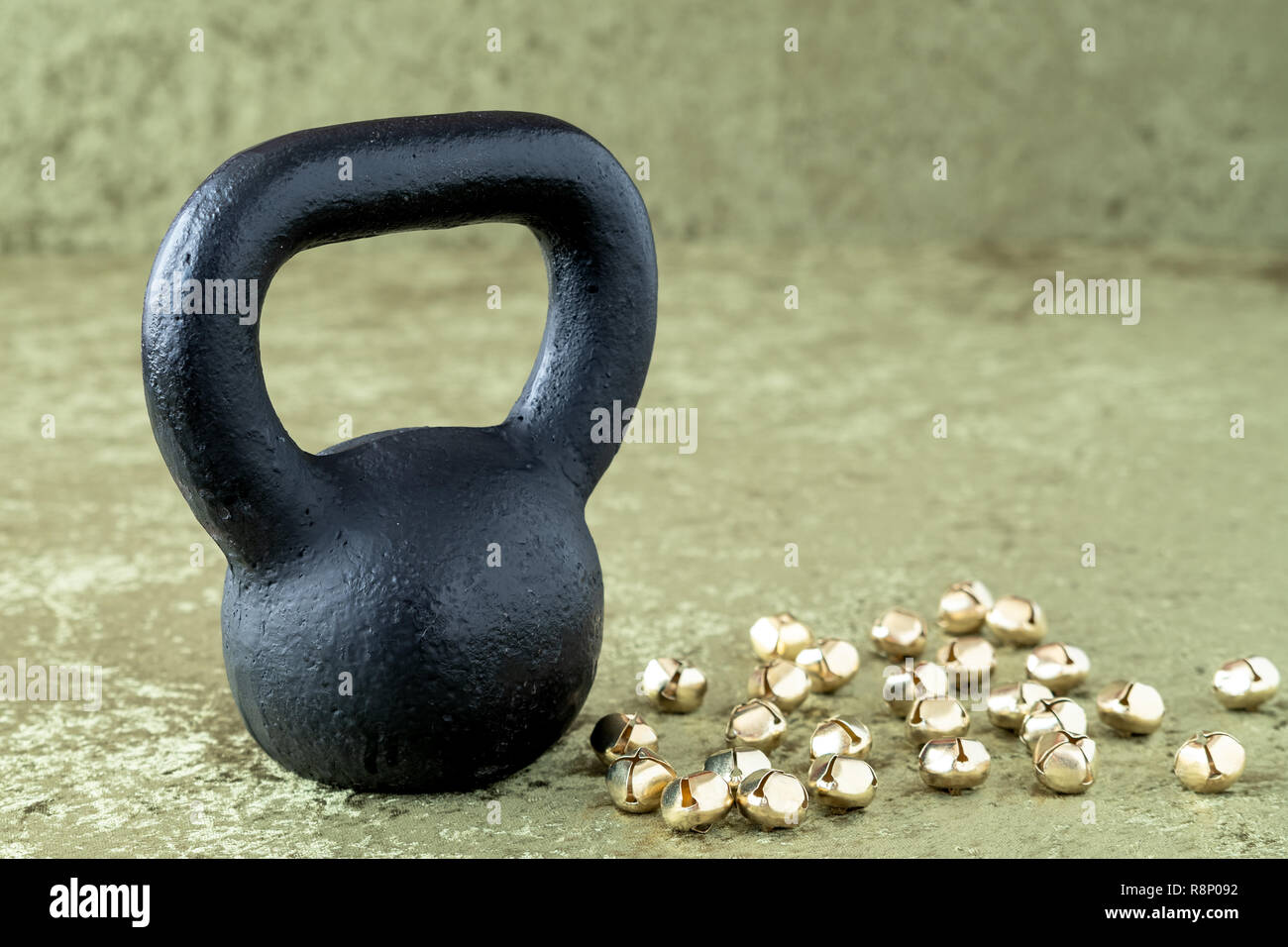Black kettlebell on a green velvet background with gold jingle bells ...