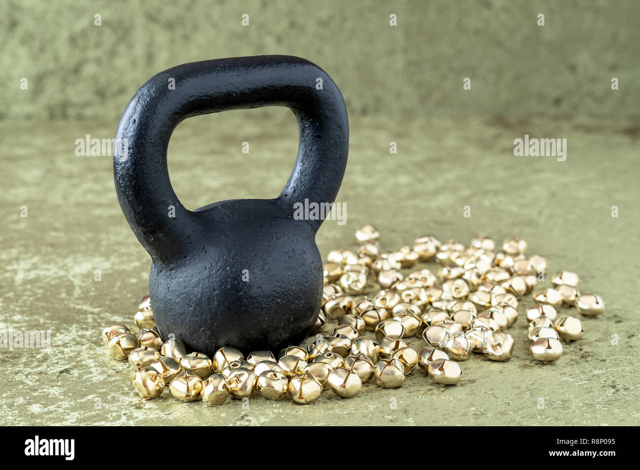 Black kettlebell on a green velvet background with gold jingle bells ...