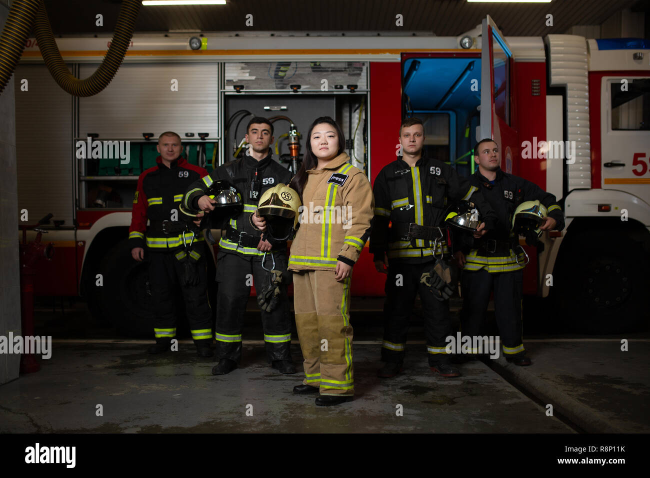 Photo of four male and female firefighters on background of fire truck ...